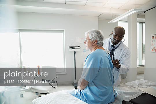 Doctor checking senior mans back in examination room - Stock Image ...