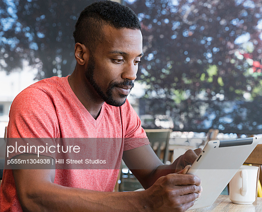 Black man using digital tablet in coffee shop - Stock Image - Everypixel