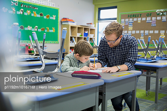 Teacher helping elementary student in classroom - Stock Image - Everypixel