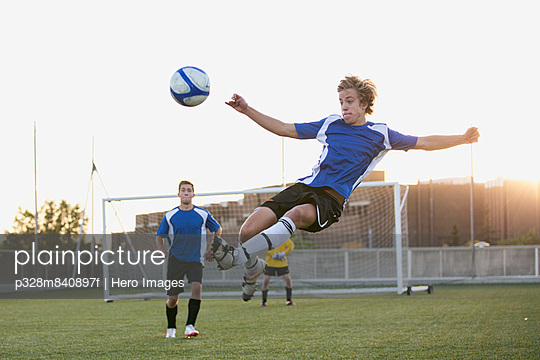 Soccer player in mid-air kicking ball. - Stock Image - Everypixel