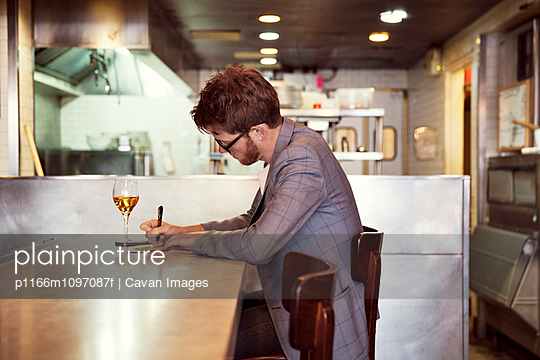 Man writing in restaurant - Stock Image - Everypixel