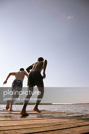 Two men jumping off dock - Stock Image - Everypixel