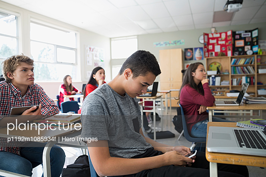 High school student texting at desk in classroom - Stock Image - Everypixel