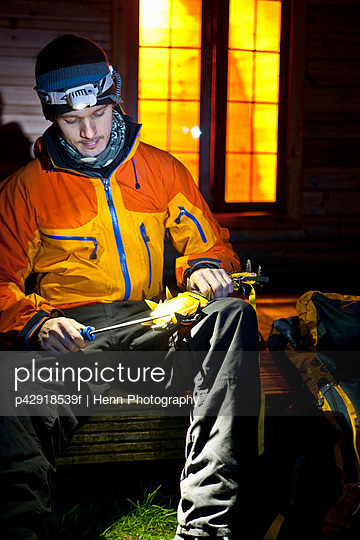 Climber sharpening ice tools outside pod - Stock Image - Everypixel