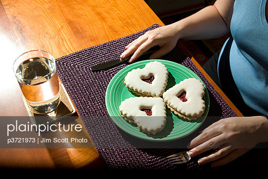 Cropped view of woman eating heart-shaped cookies - Stock Image ...
