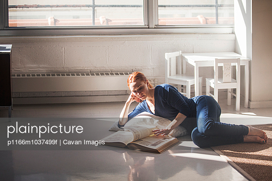 Woman laying on floor, reading book - Stock Image - Everypixel
