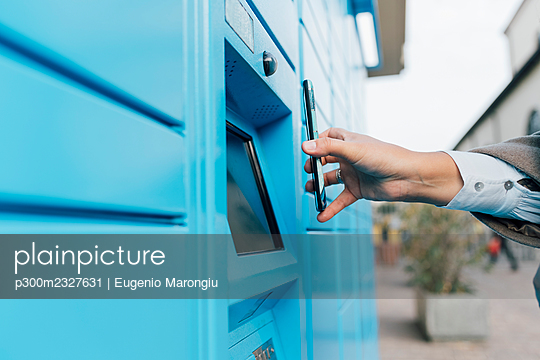 plainpicture - plainpicture p300m2327631 - Woman scanning QR Code with ...