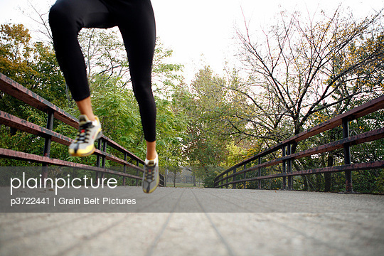 Below waist view of young woman running on footbridge - Stock Image ...