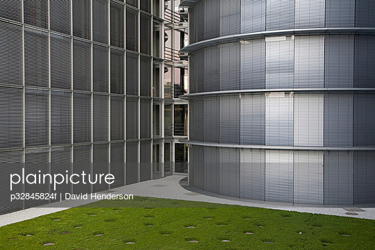 Grassy courtyard bordered by a curved metal wall - Stock Image - Everypixel