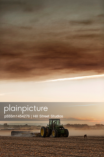 Tractor driving in crop field - Stock Image - Everypixel