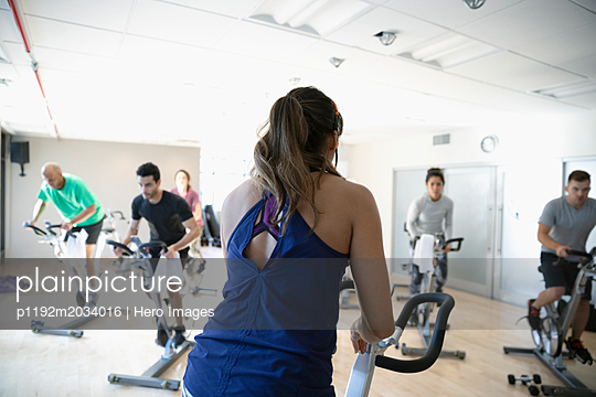 Female instructor on exercise bike leading spin class in gym - Stock ...