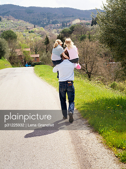 Father carrying two girls on shoulders - Stock Image - Everypixel