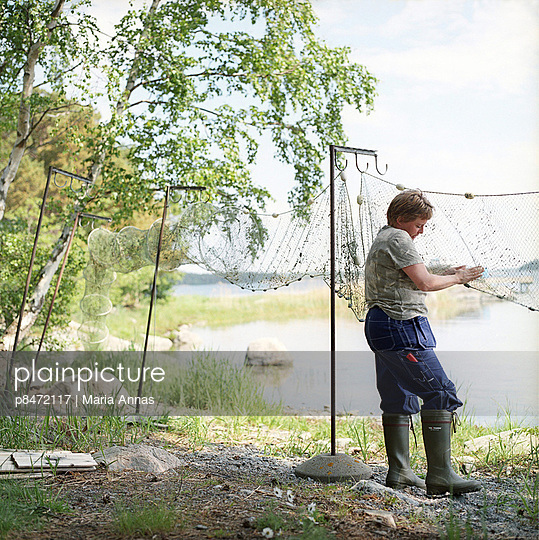 Woman Cleaning Fishing Net - Stock Image - Everypixel