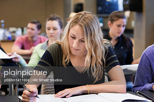 Student writing at desk in classroom - Stock Image - Everypixel