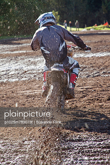 Rear view of a motorcyclist riding in the dirt road - Stock Image ...