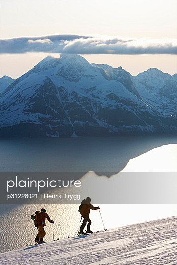 Two people skiing, lake and mountain in background - Stock Image ...