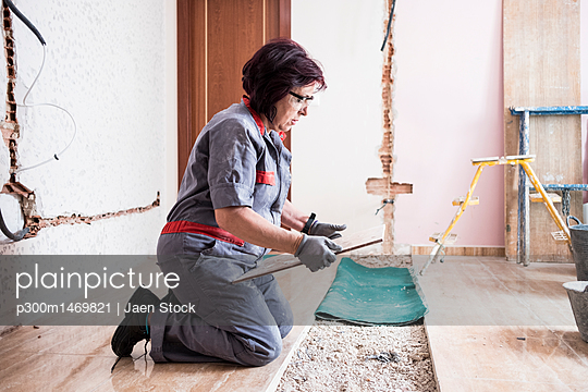 Senior woman laying tiles at construction site - Stock Image - Everypixel