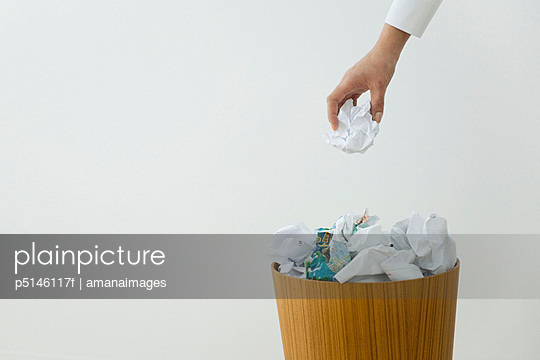 Hand dropping crumpled paper into wastepaper bin - Stock Image - Everypixel